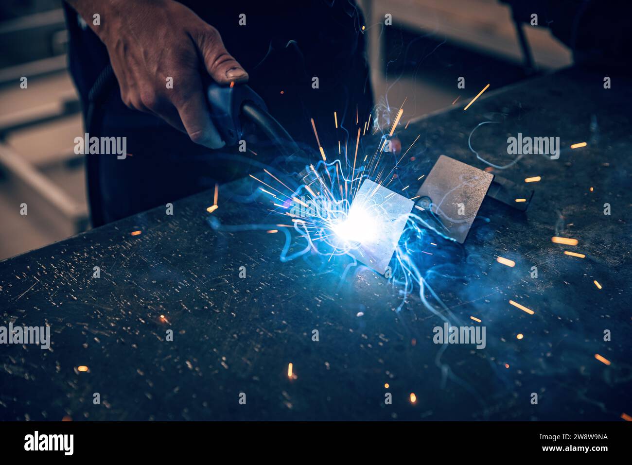 Male worker hand welding steel rack, close up. Sparks in metalworking ...