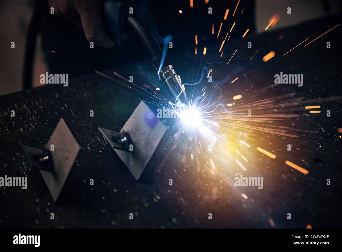 Male worker hand welding steel rack, close up. Sparks in metalworking ...