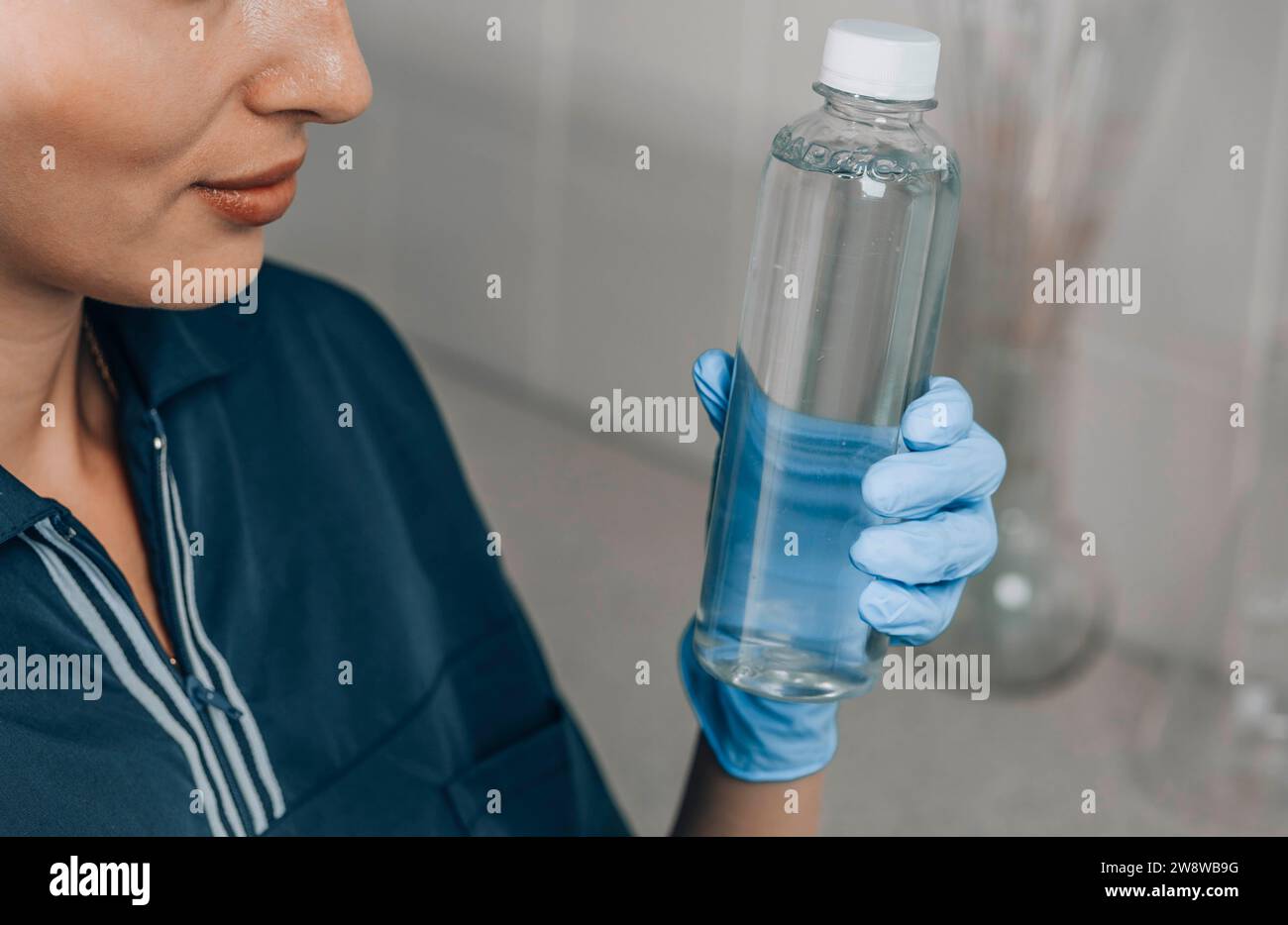 Woman scientist holding bottle with transparent liquid in her hands in ...