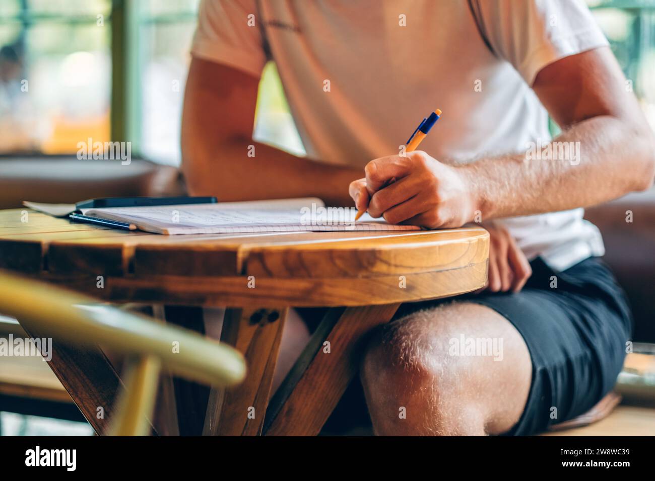 Left handed man hand with pen writing on notebook Stock Photo - Alamy