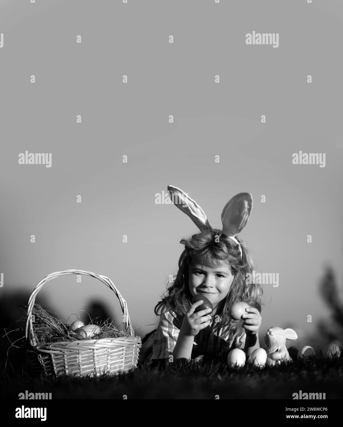 Child with easter eggs in basket outdoor. Boy laying on grass in park ...