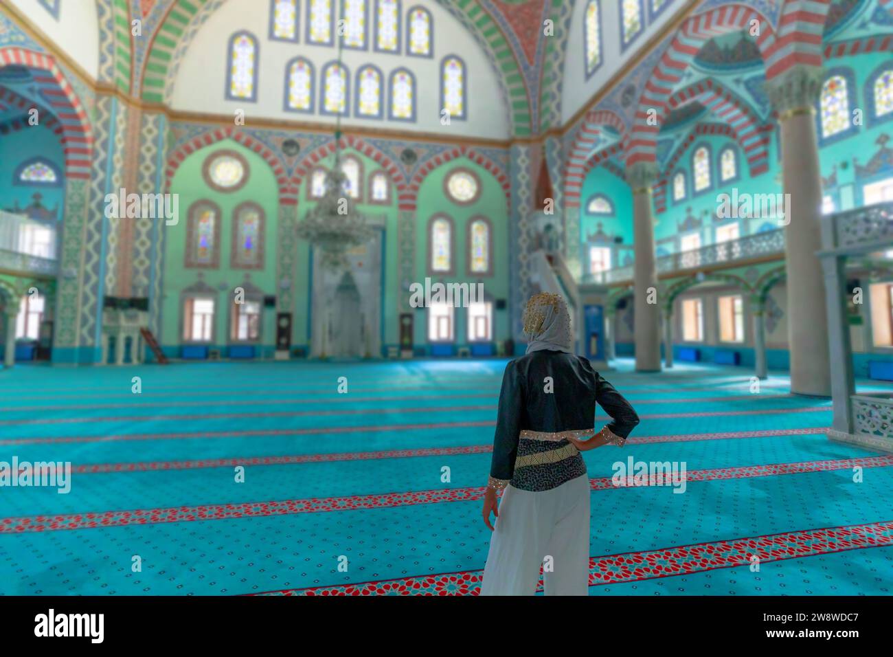 Woman in hijab dress looking at the mihrab inside a historic mosque in ...