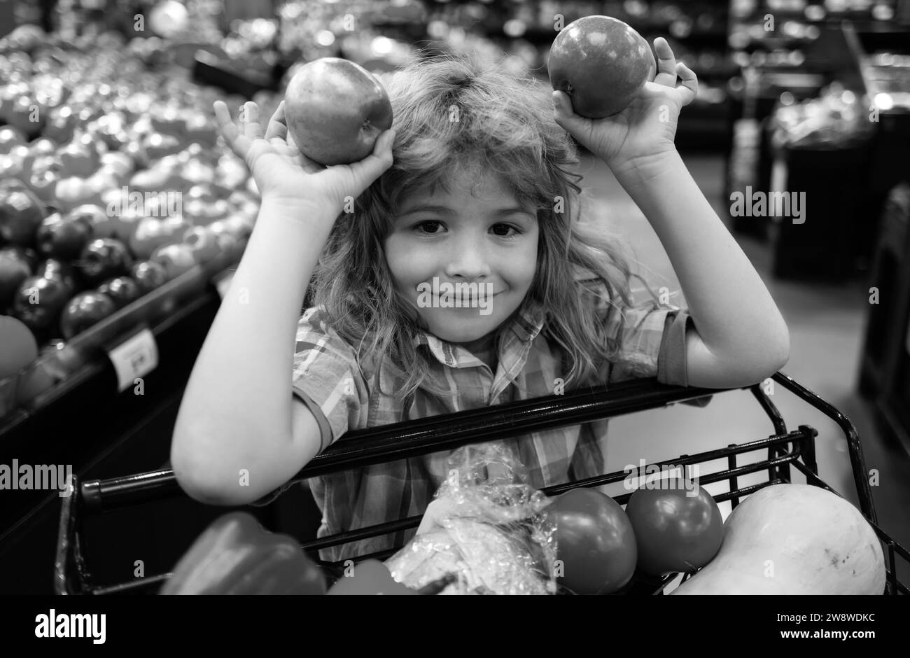 Child choosing a apple in a store. Funny little child smile and holding ...