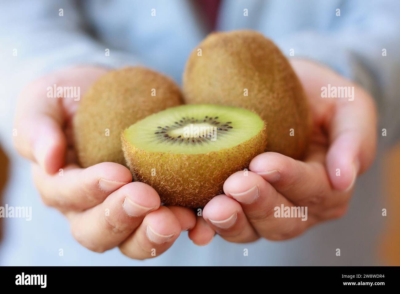 holding fresh kiwi fruit in hands Stock Photo - Alamy