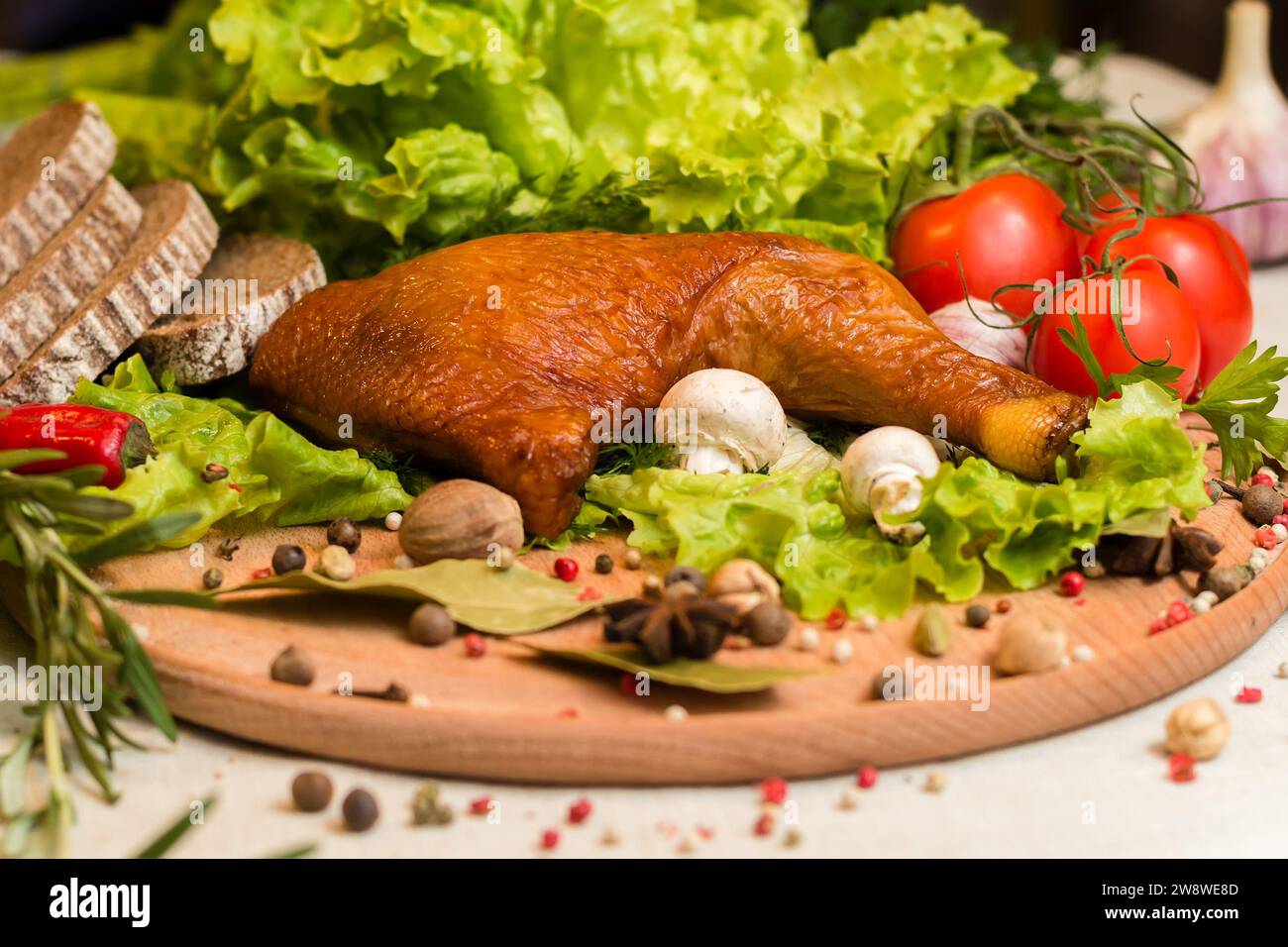 Smoked chicken quarter with fresh herbs, tomatoes, slices of bread and ...