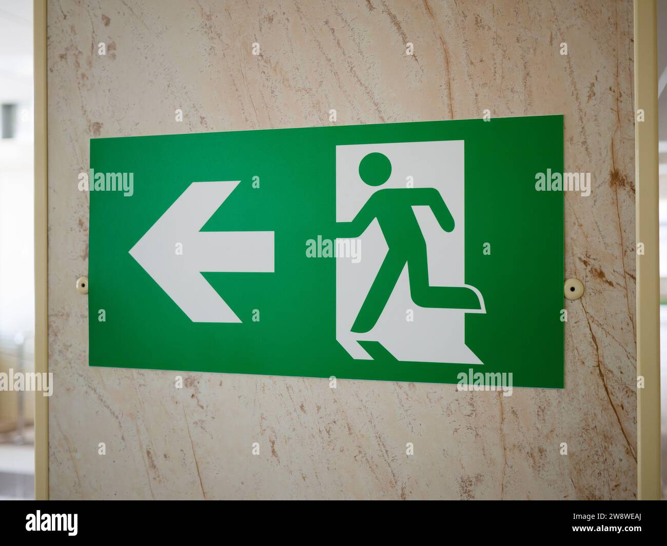 A green emergency exit sign indicating a safe exit to a safe area. Fire ...