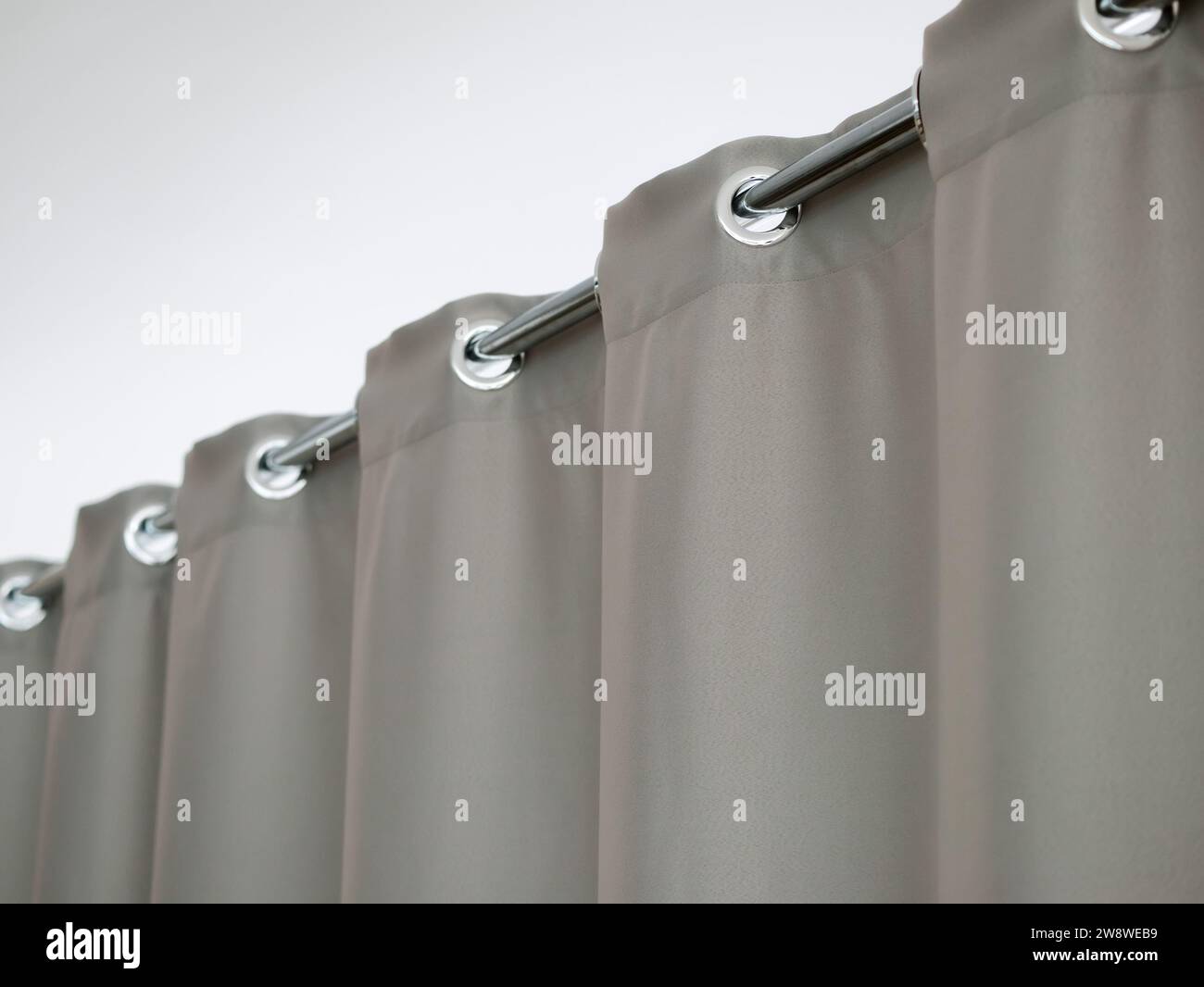 Heavy thick gray curtain with grommets on the stainless tube of the ...