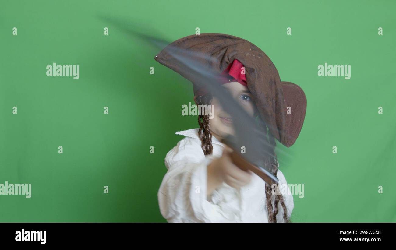 Portrait of a cute boy dressed as a pirate slicing air with cutlass toy ...
