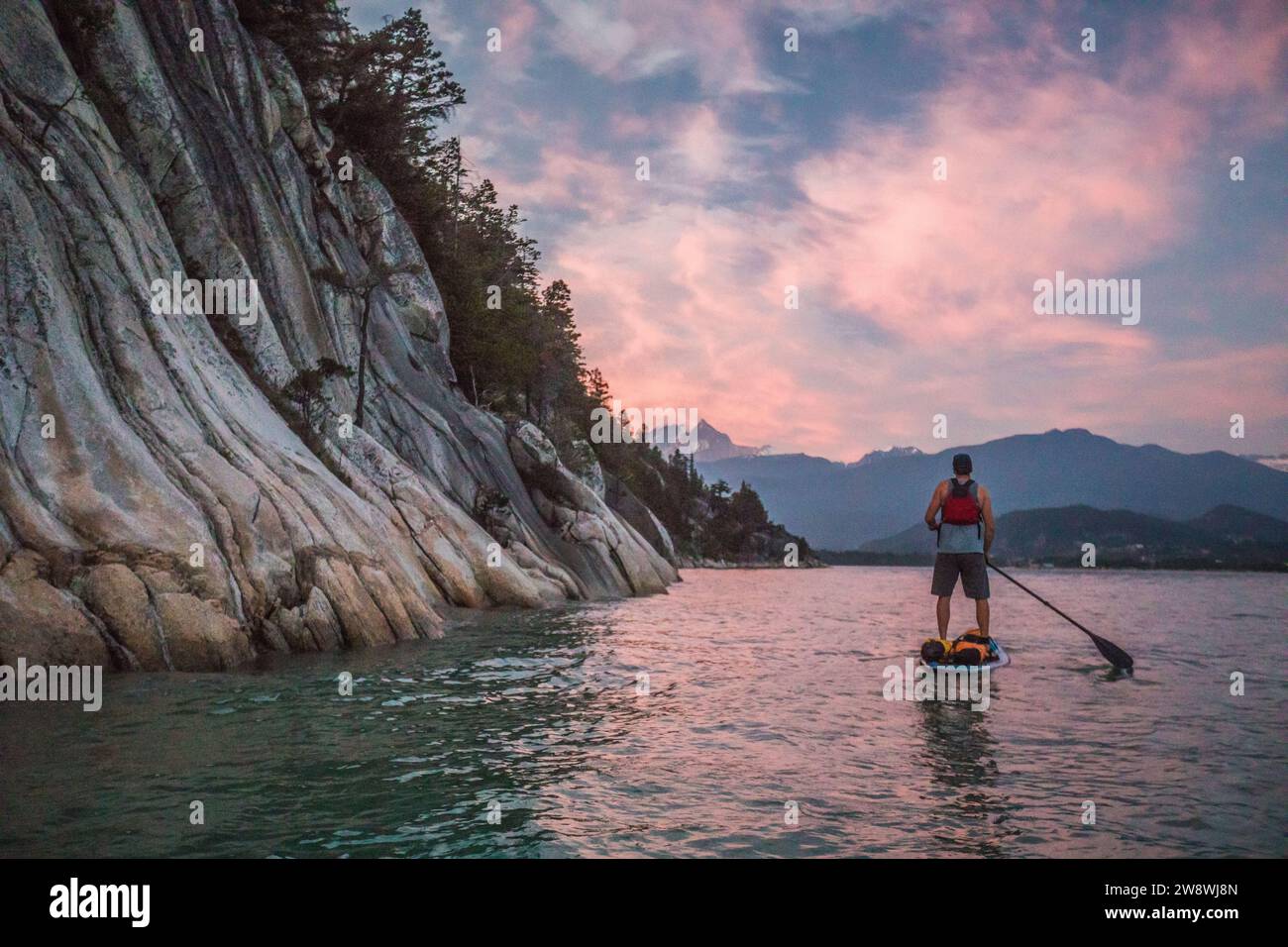 Rear view of man paddle boarding next to sea cliffs, Howe Sound Stock ...