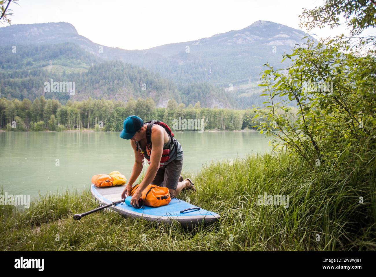 SUP Paddle boarder secures dry bags and gear before paddling Stock ...