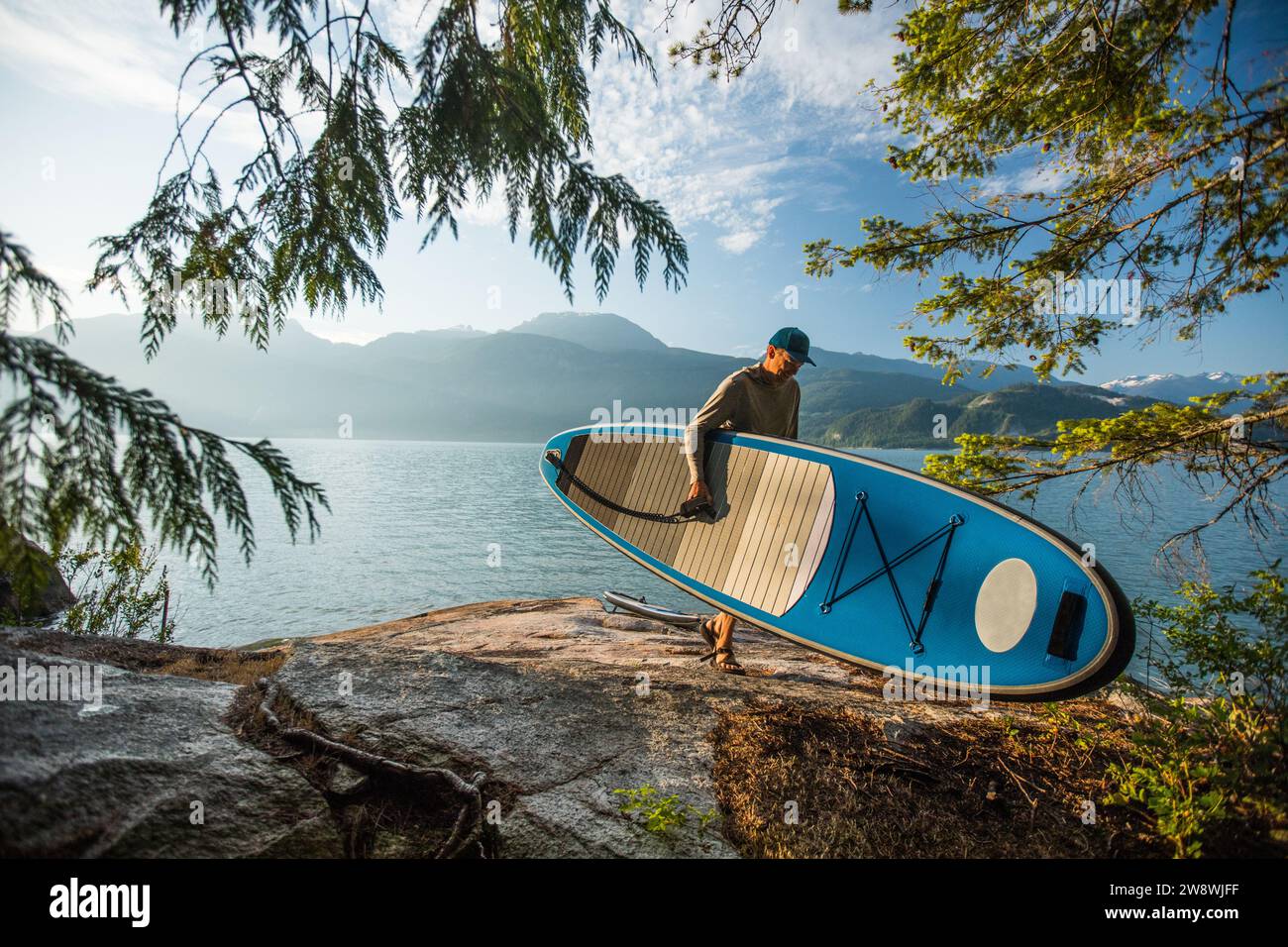 Side view of man carrying paddle board at destination Stock Photo - Alamy