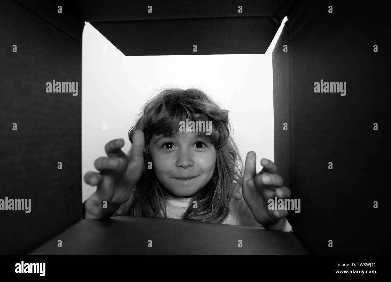 Surprised child boy unpacking, opening carton box and looking inside ...