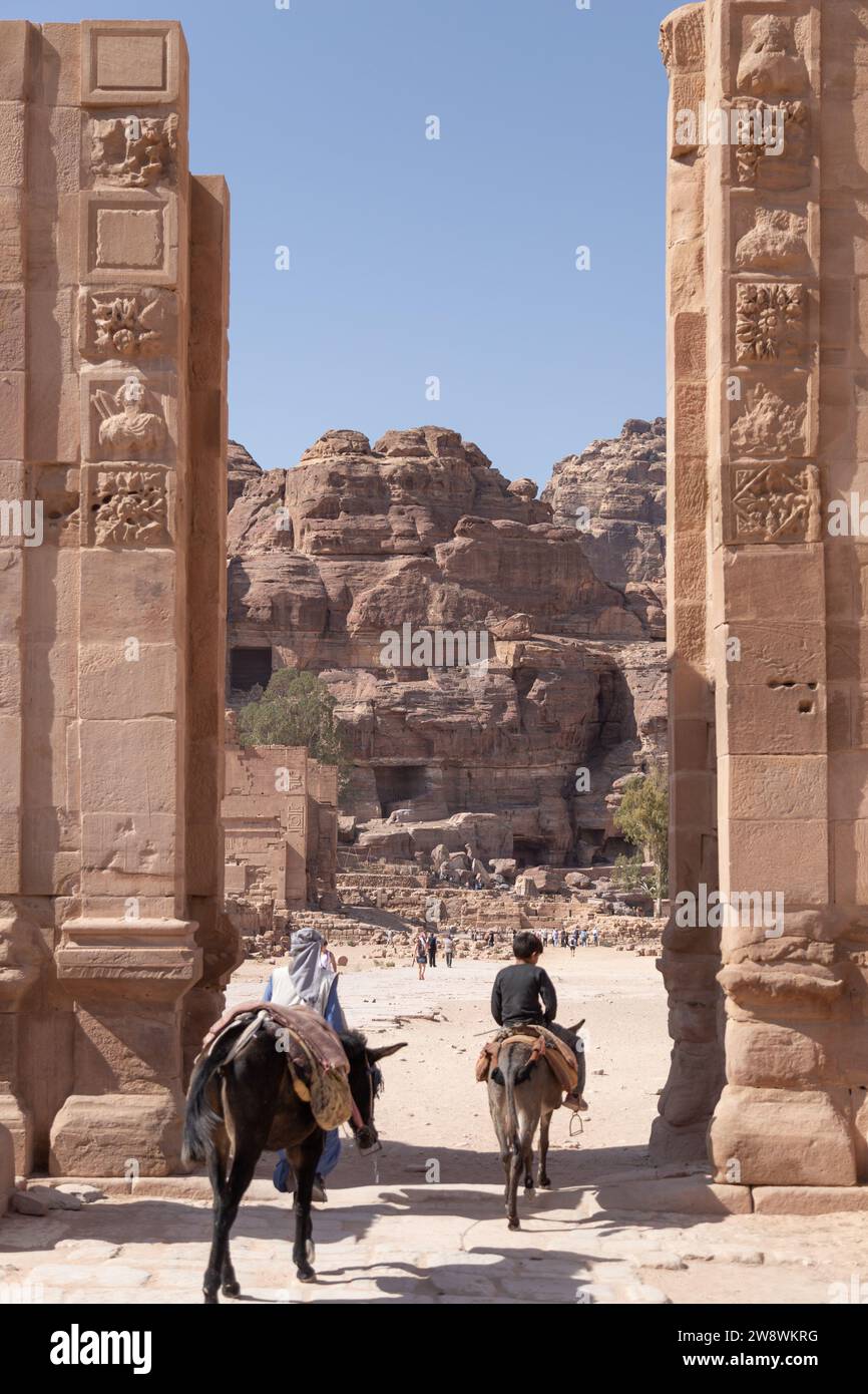 Two kids riding donkeys, passing through ancient gate in Petra Stock ...