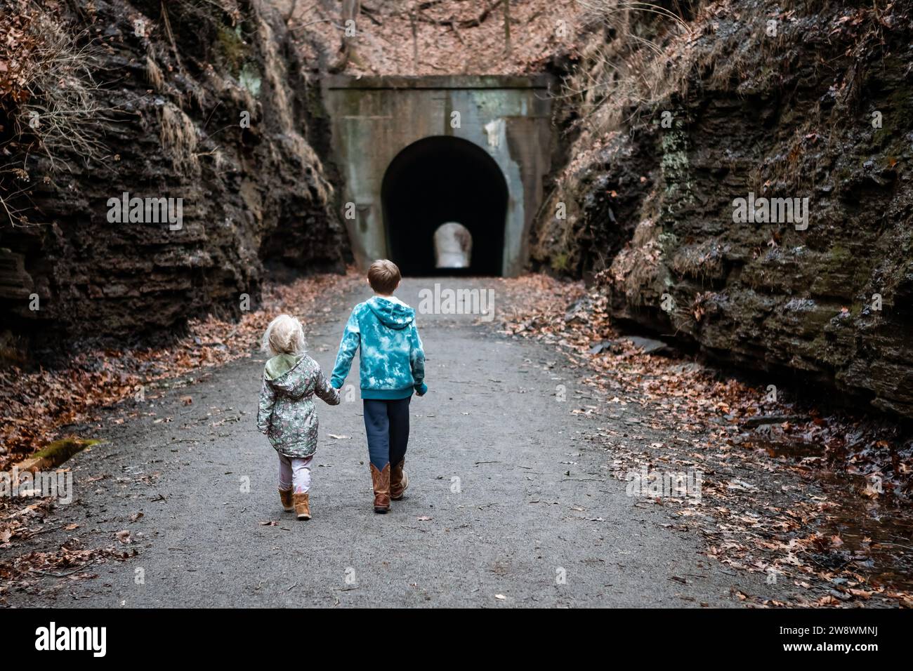 Children holding hands walking toward underground tunnel on hike Stock ...