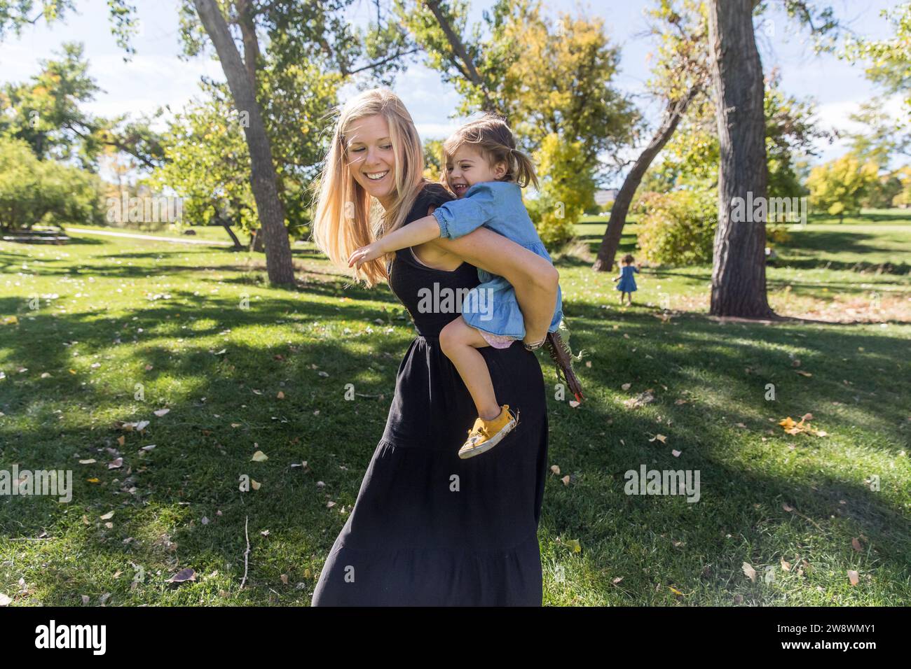 Mom and daughter laughing in park with piggyback ride Stock Photo - Alamy