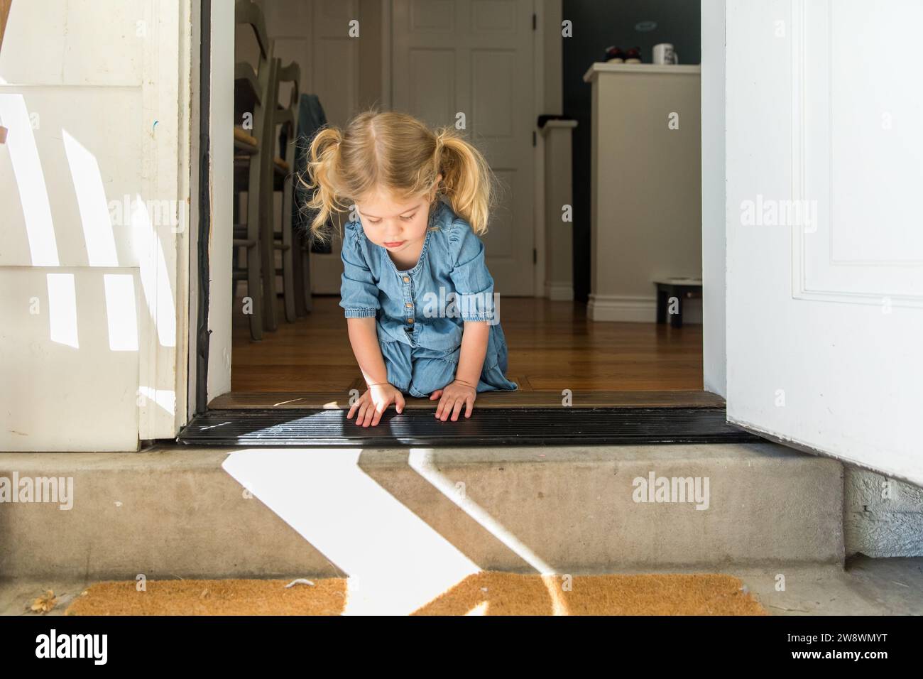 Young girl crawling out of door to porch in sunlight Stock Photo - Alamy