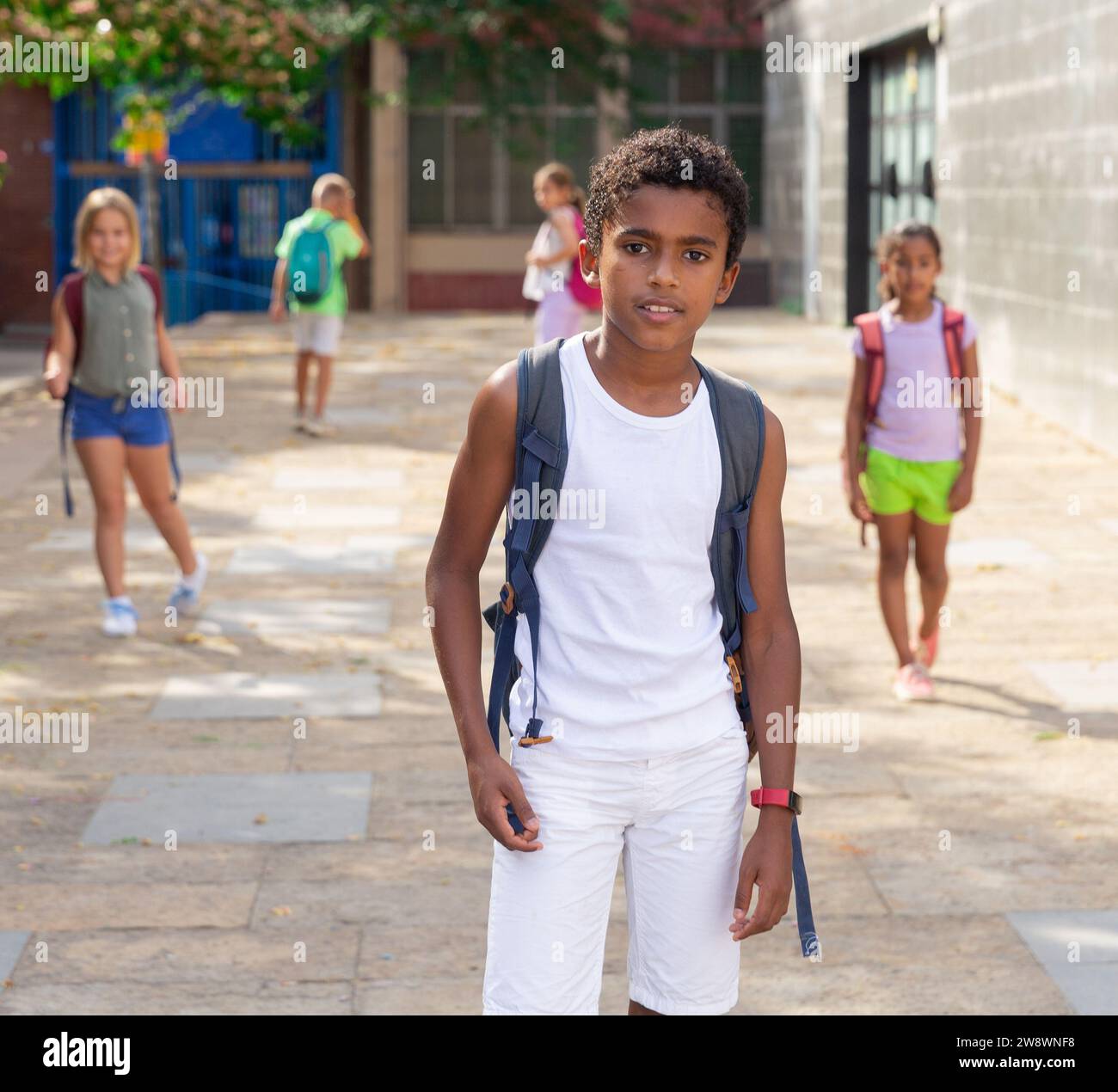 Boy with backpack standing in schoolyard Stock Photo - Alamy