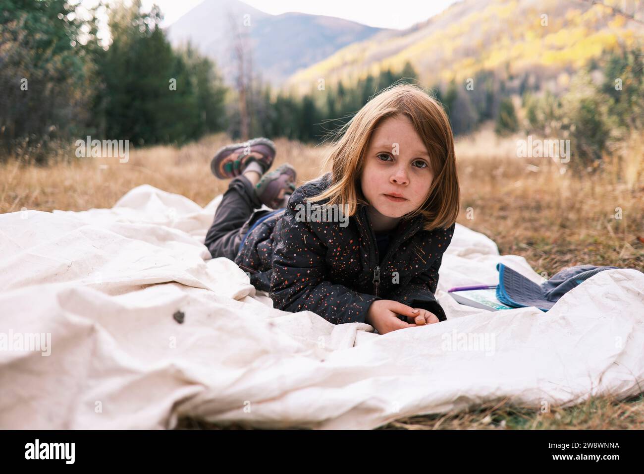 Young girl lying down outdoors, surrounded by mountains Stock Photo - Alamy
