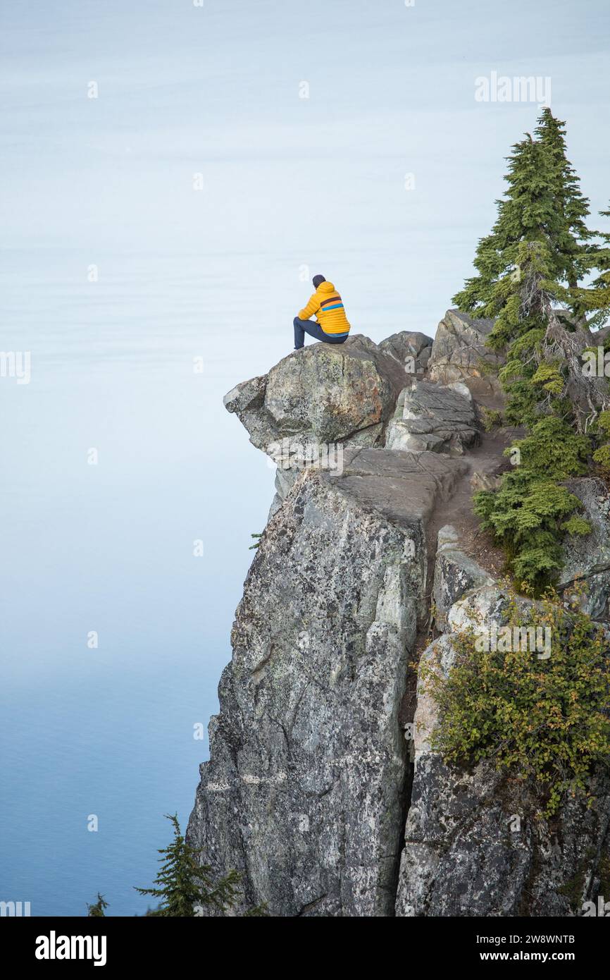 Man sitting on cliff overlooking the Pacific Ocean far below Stock ...