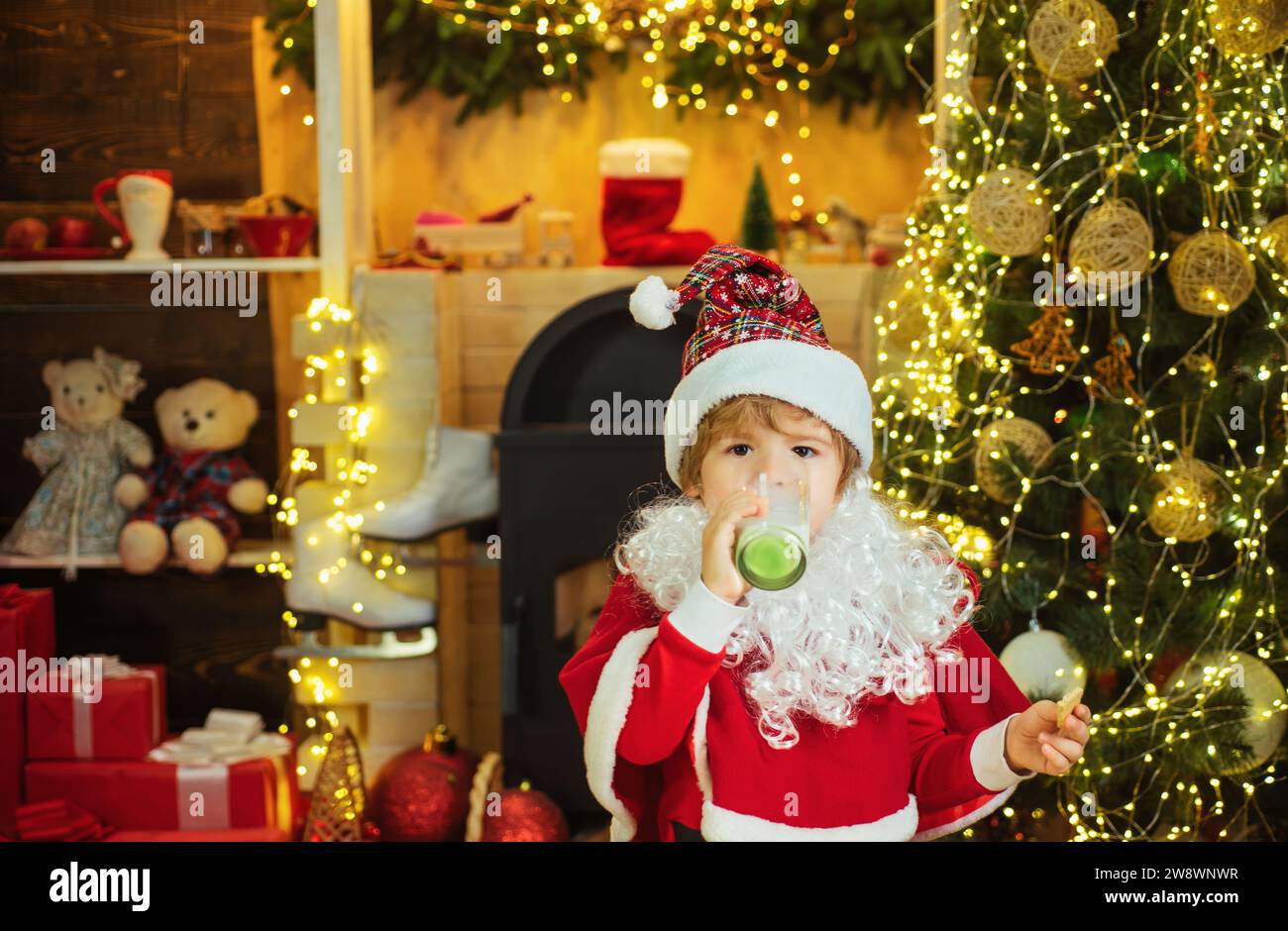 Kid Santa Claus enjoying in served gingerbread cake and milk. Greeting ...