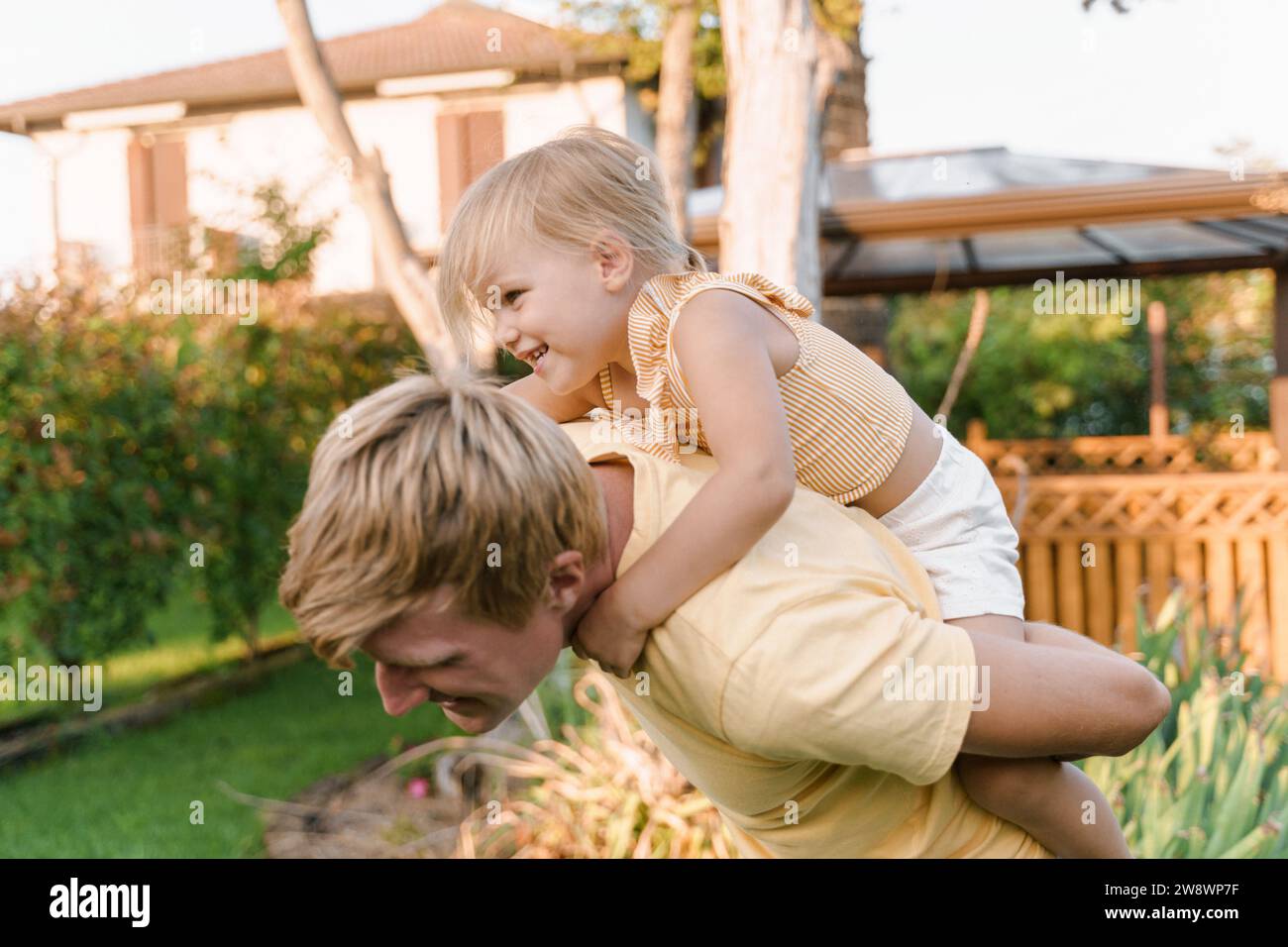 Father gives his happy daughter piggyback rides in the backyard Stock ...