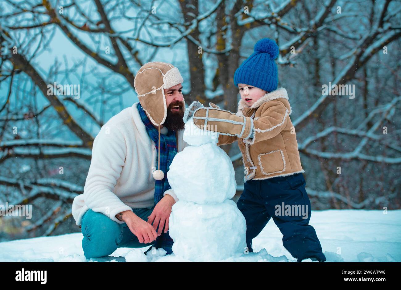 Father and son making snowman in the snow. Handmade funny snowman ...