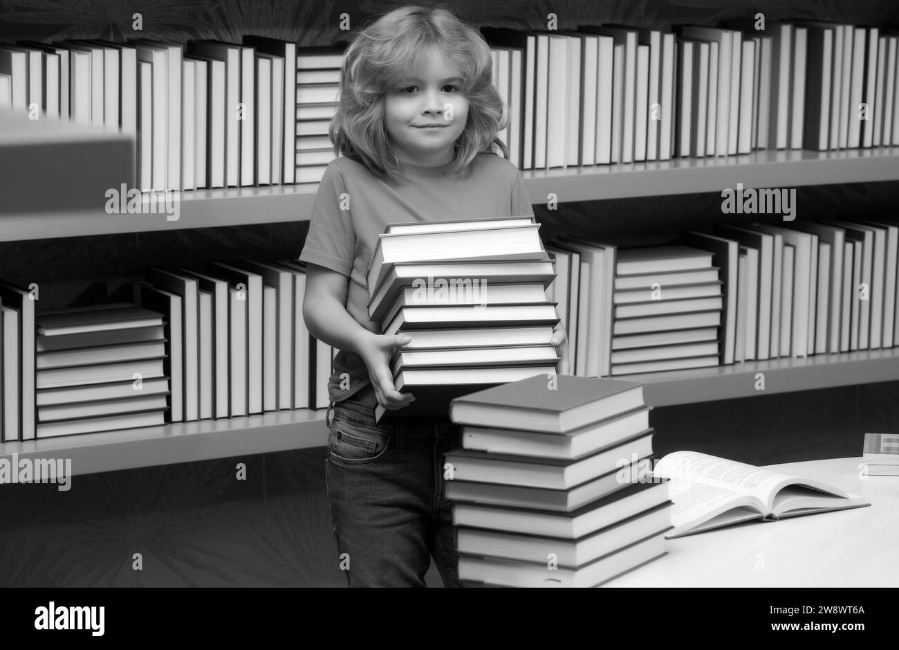 School boy with stack of books in library. School child student ...