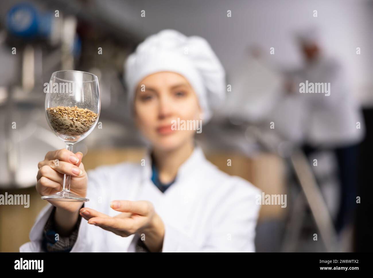 Female brewmaster holding glass of malt Stock Photo - Alamy