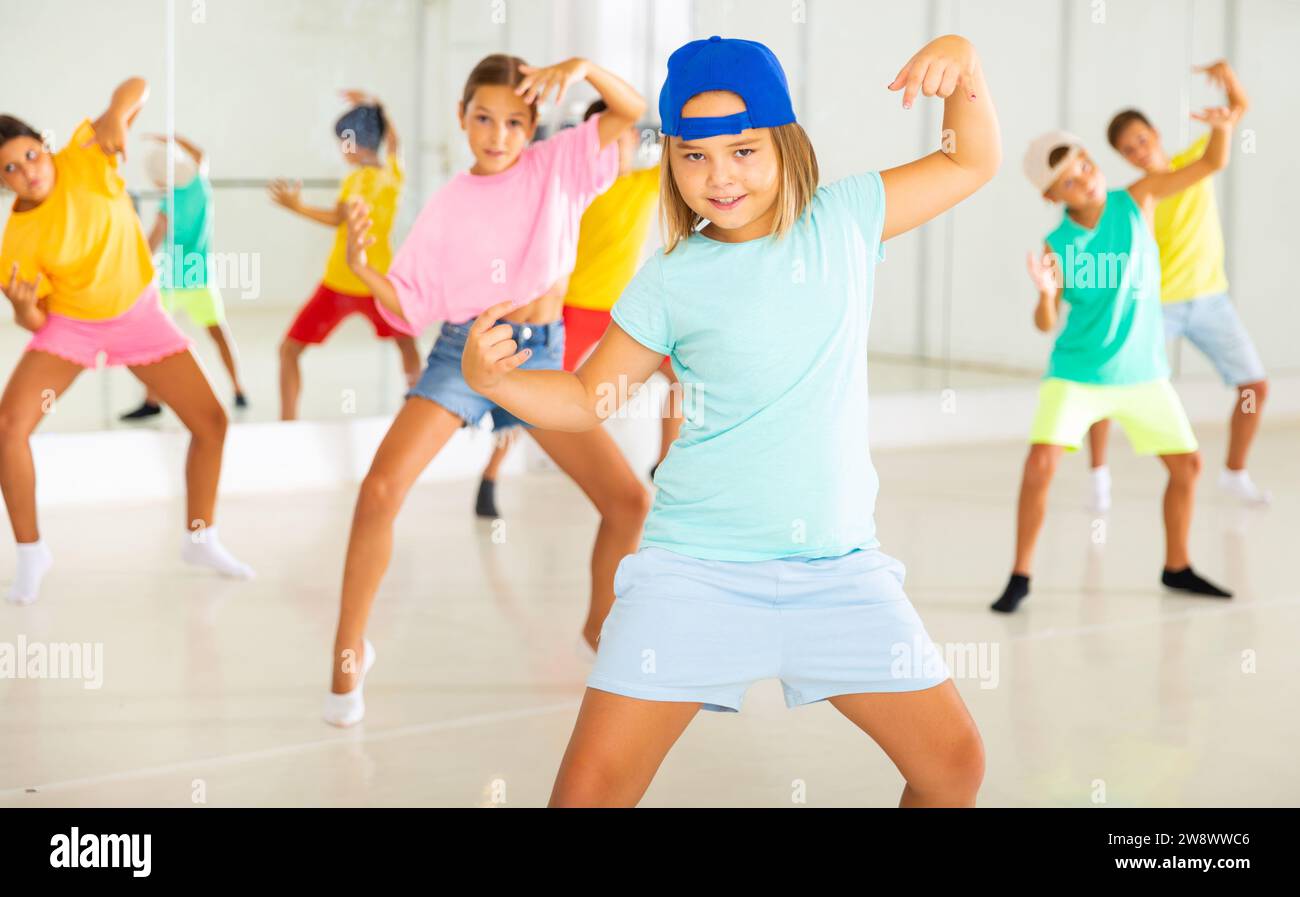 Preteen girl practicing hip-hop movements during group dance lesson ...