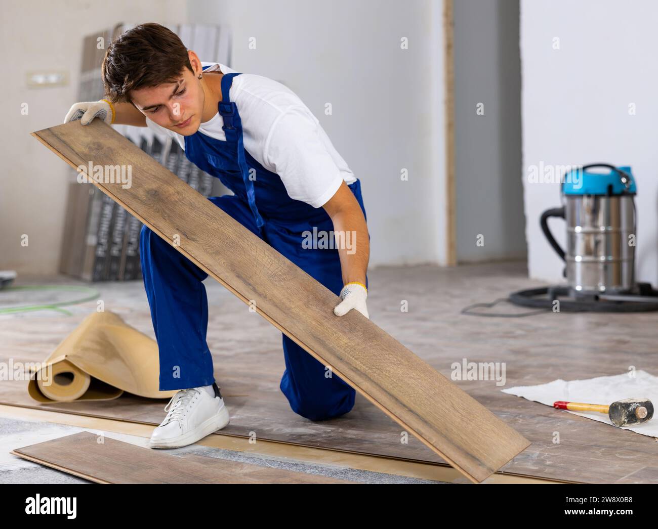Professional male builder laying laminate flooring in room being ...