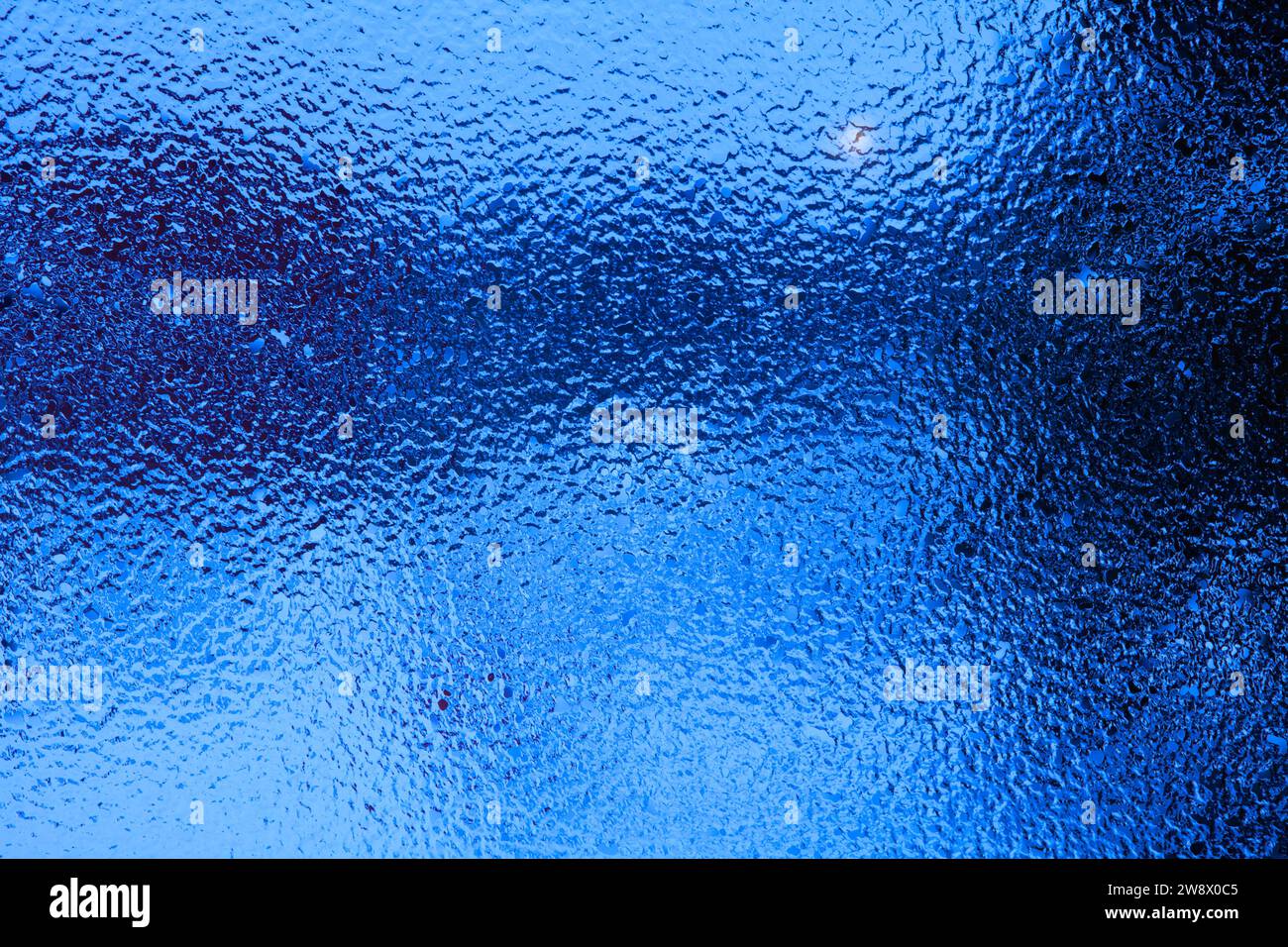 Frosty, frozen raindrops on a window glass. Nightfall, blue color ...