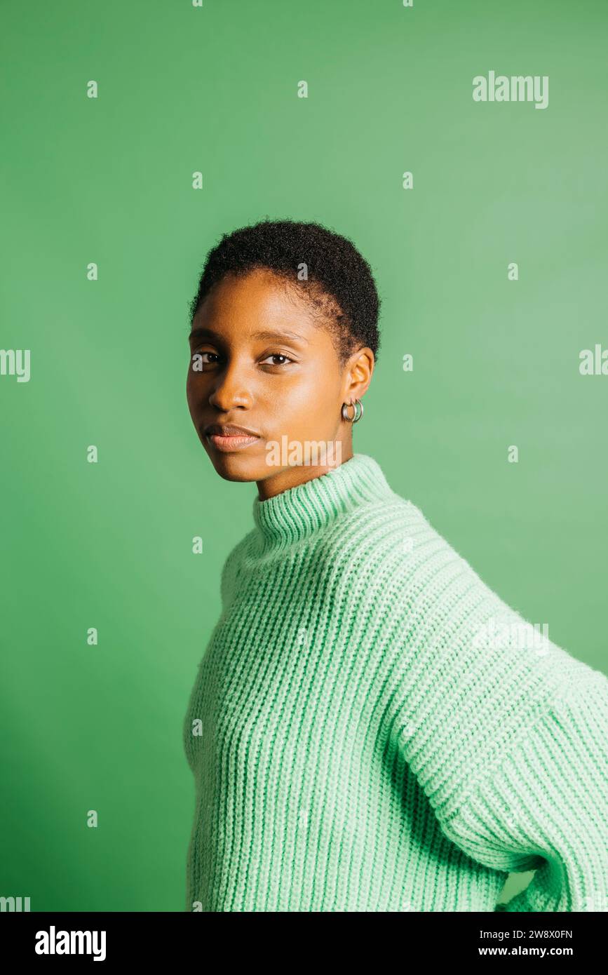Portrait of a serious young beautiful woman wearing green clothes ...