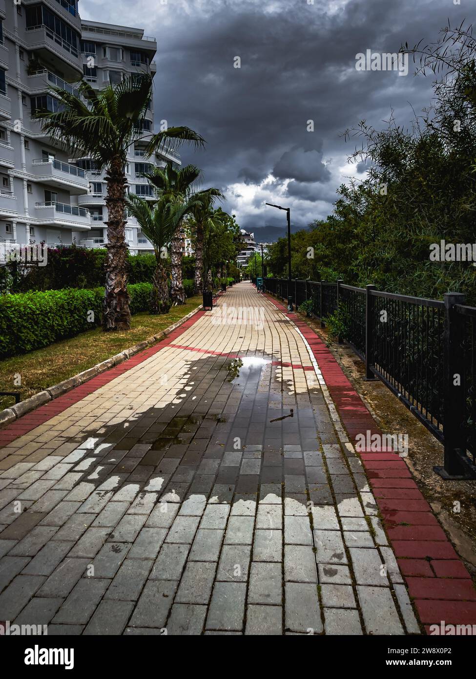 A dark cold path under a scenic sky in winter with a small water puddle ...