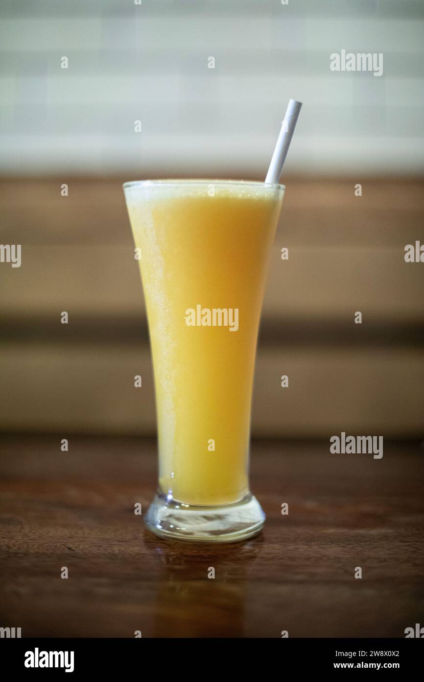 A close-up photo of a glass of orange juice with a single, slender ...