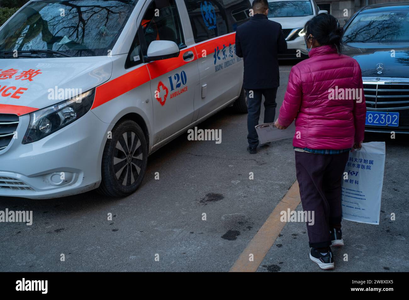 A woman holding a bag of X-rays as an ambulance passes by her in a ...