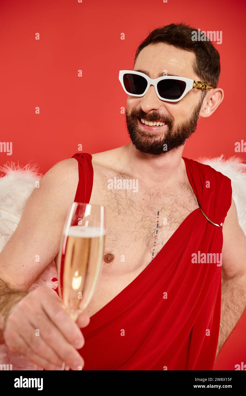 bearded man in sunglasses and cupid costume smiling with champagne ...