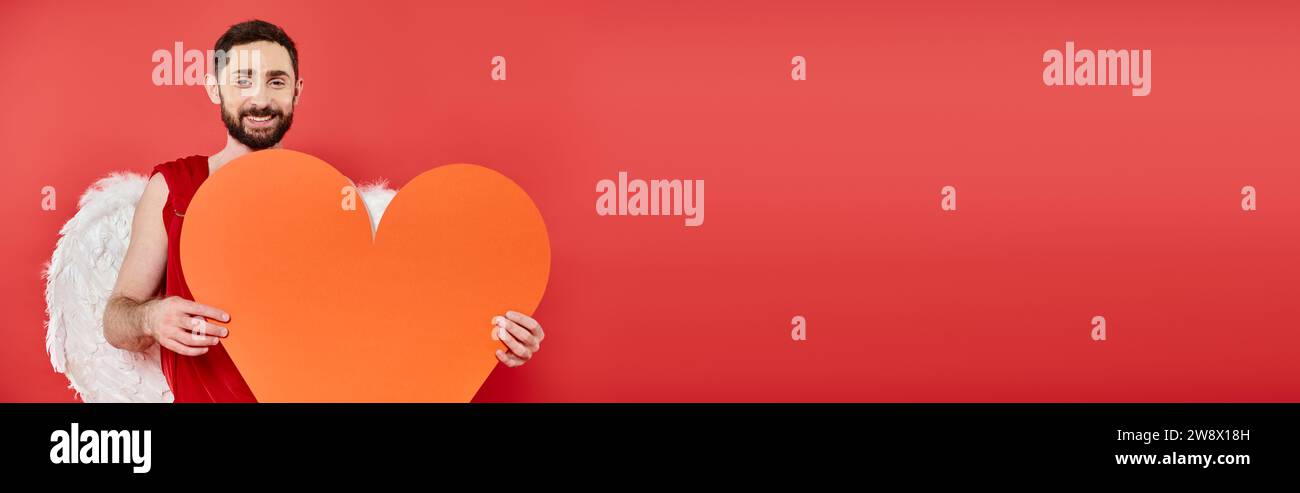 romantic bearded man in cupid costume with huge paper heart on red ...