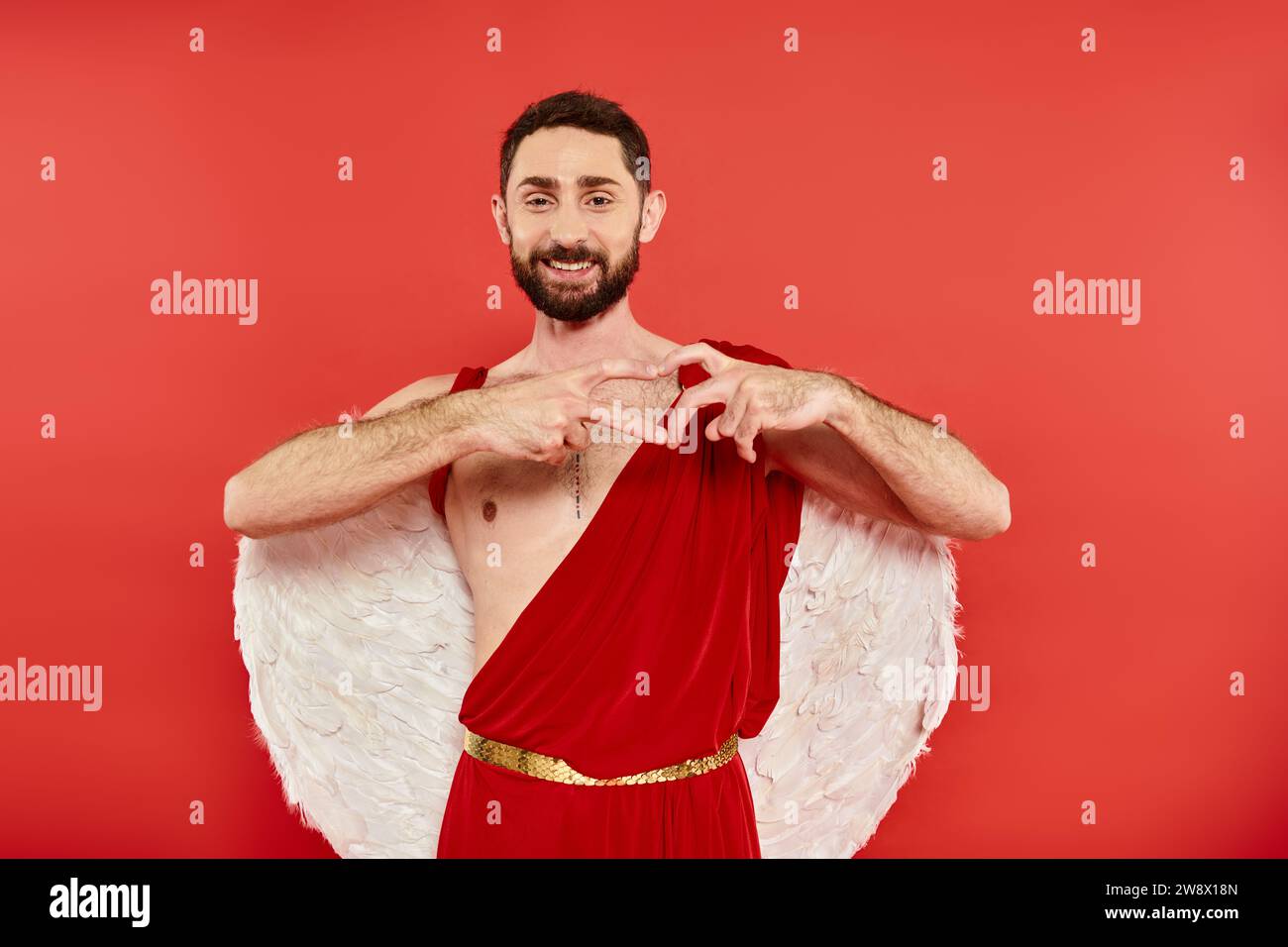 pleased bearded cupid man showing heart sign with fingers and smiling ...