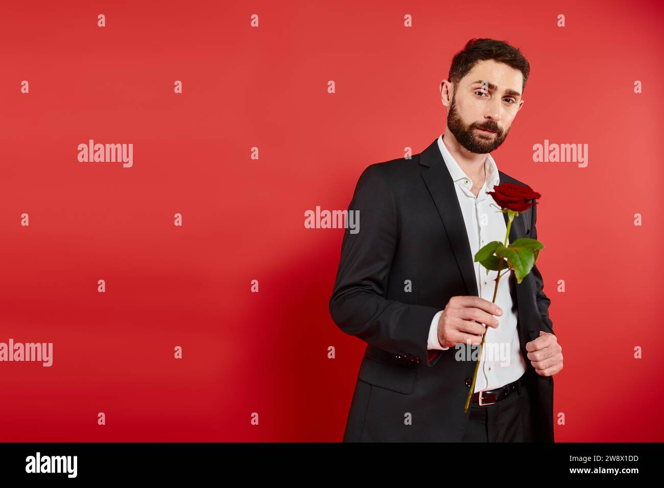 well-dressed charismatic man in black suit with red rose looking at ...