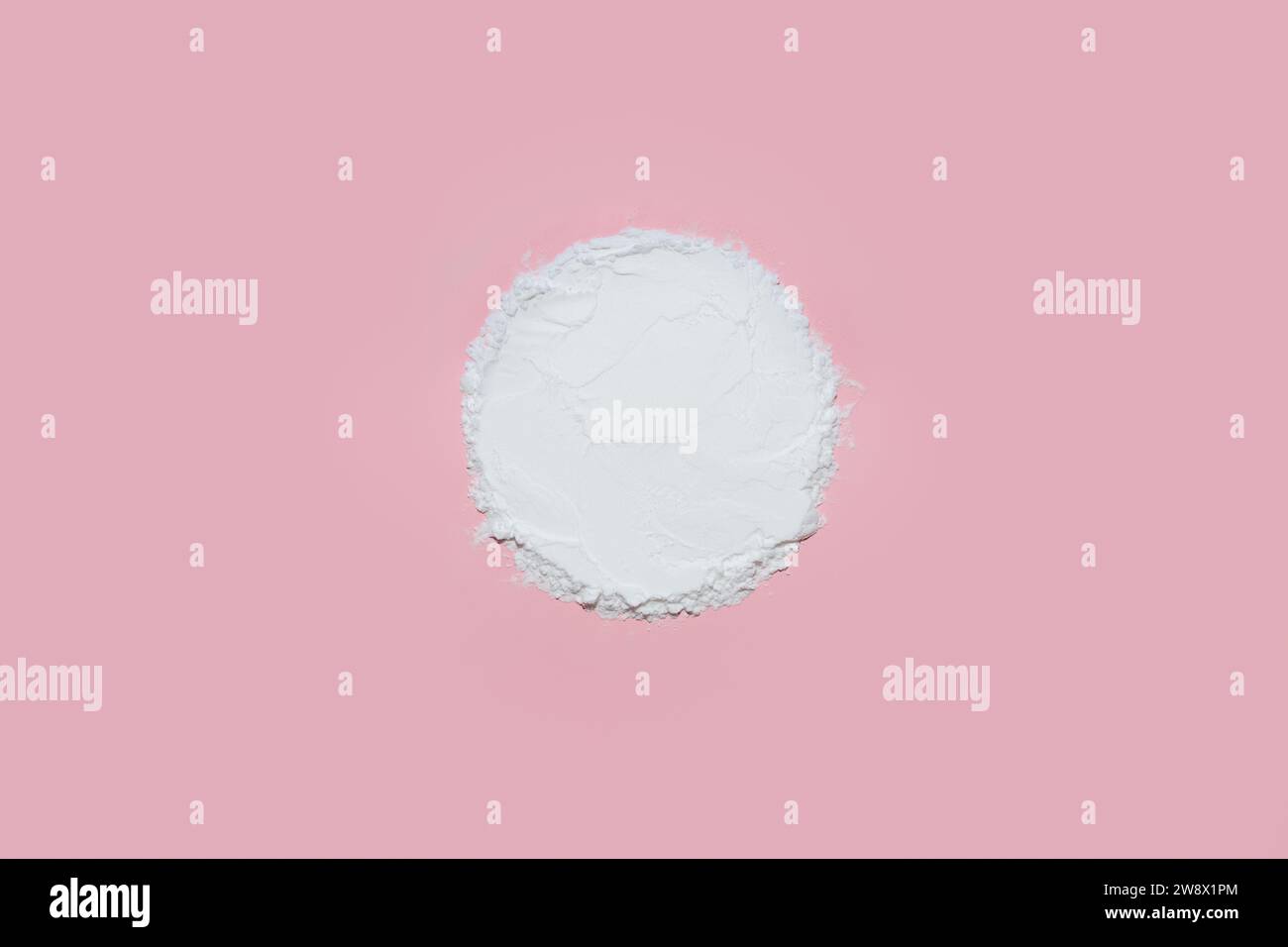 Clear white face powder with an empty circle on a soft pastel pink ...