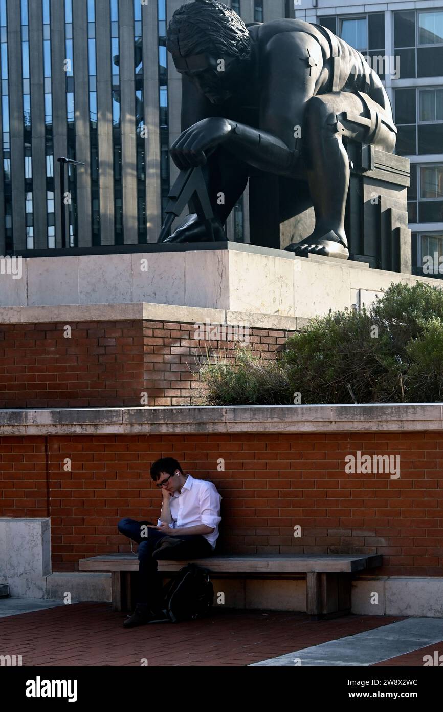 Man reading a book under the bronze statue of Sir Isaac Newton by ...