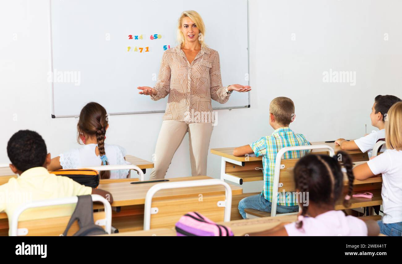 Woman teacher is giving interesting lecture for primary school students ...