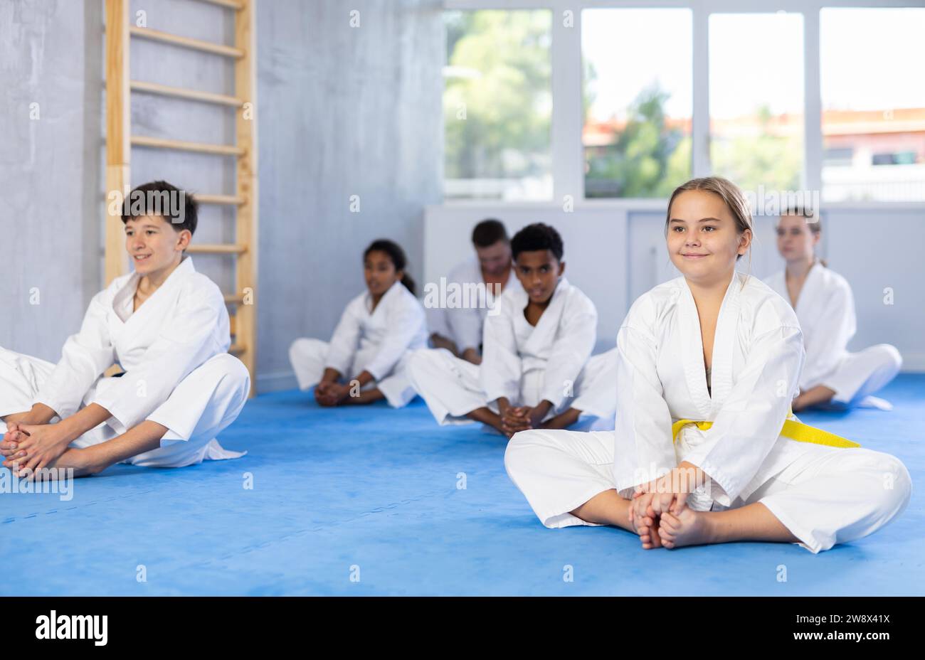 Group of multinational children in white kimono sits in butterfly pose ...
