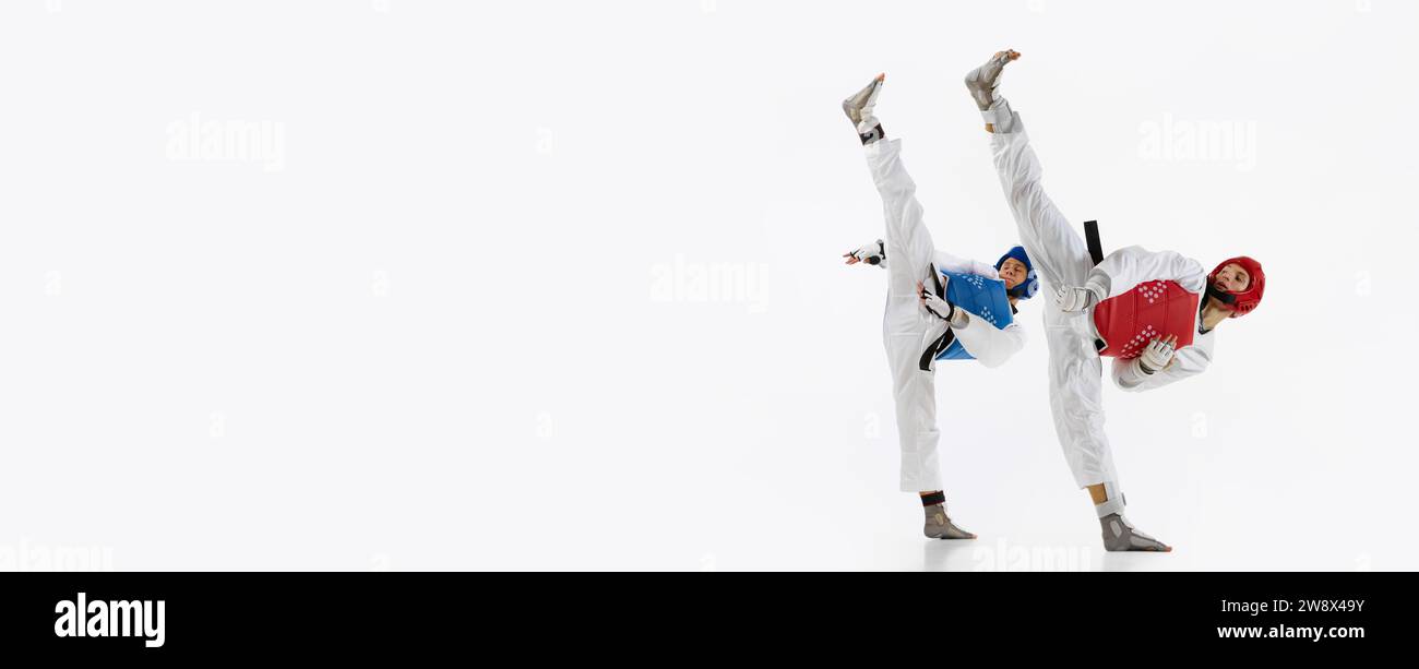 Flexible, athletic young men, taekwondo athletes in kimono and helmet ...