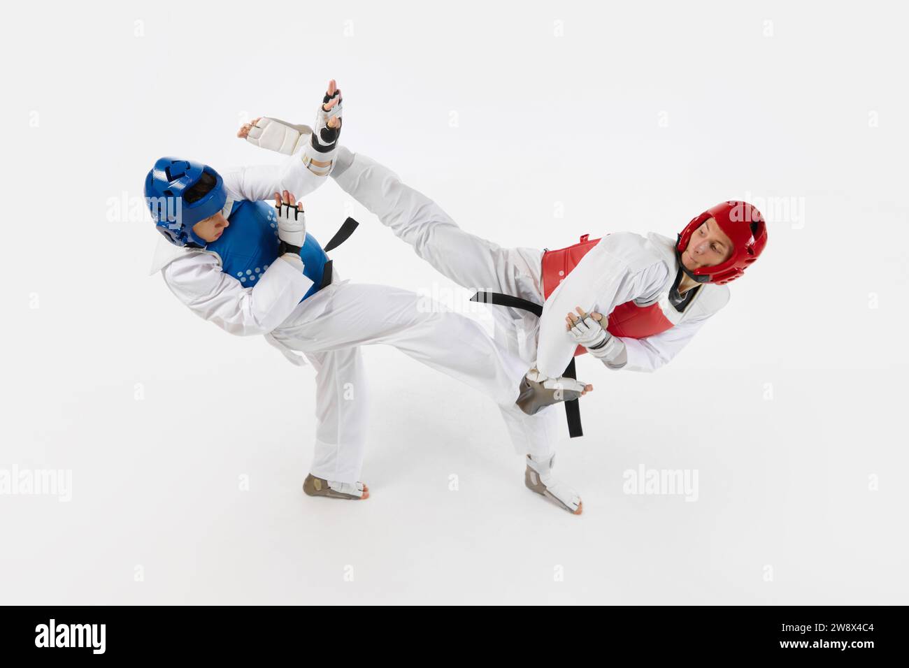 Competitive young men, taekwondo athletes fighting, hitting with legs ...