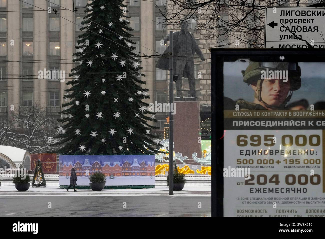A woman walks past a Christmas tree and a statue of Soviet Union ...