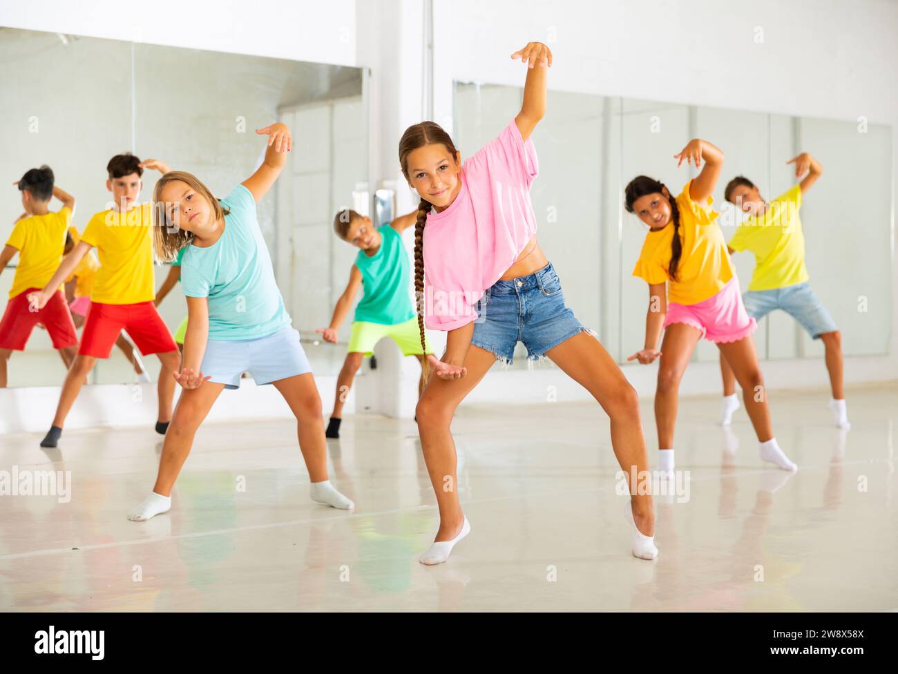 Preteen girl practicing hip-hop movements during group dance lesson ...