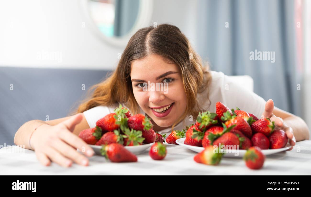 Young woman eating strawberry at home Stock Photo - Alamy