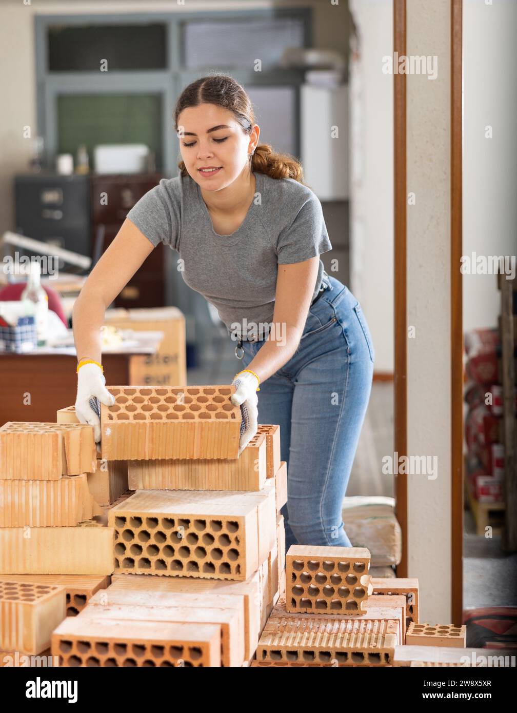 Young woman stacking bricks in building site Stock Photo - Alamy