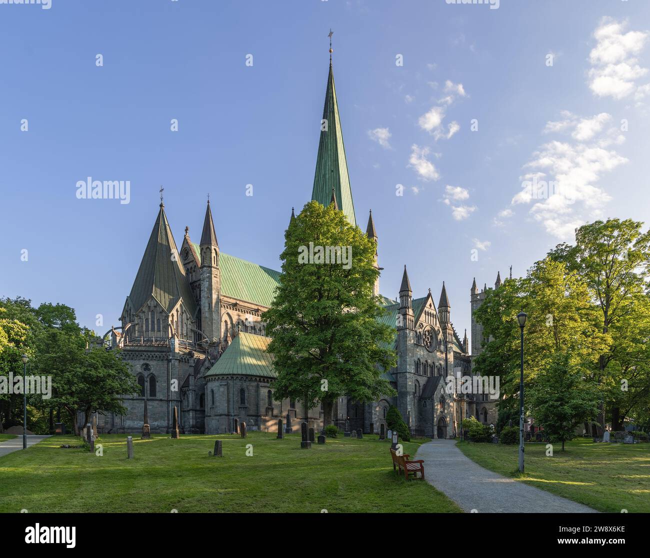 Nidaros Cathedral (Nidarosdomen) in Trondheim, Norway, enveloped by lush green trees and a well ...